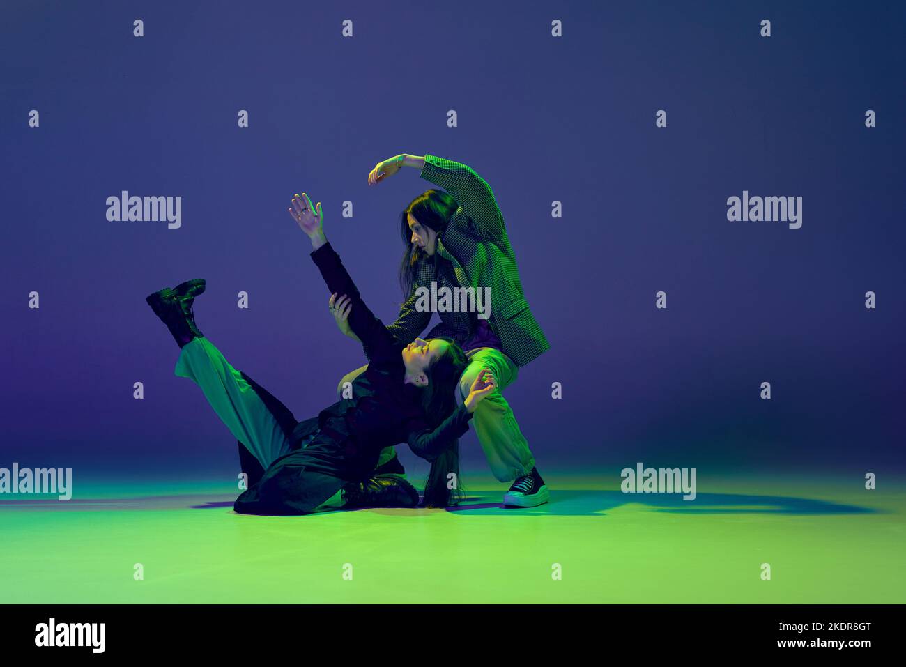 Stylish young girls in casual clothes dancing experimental style dance ...