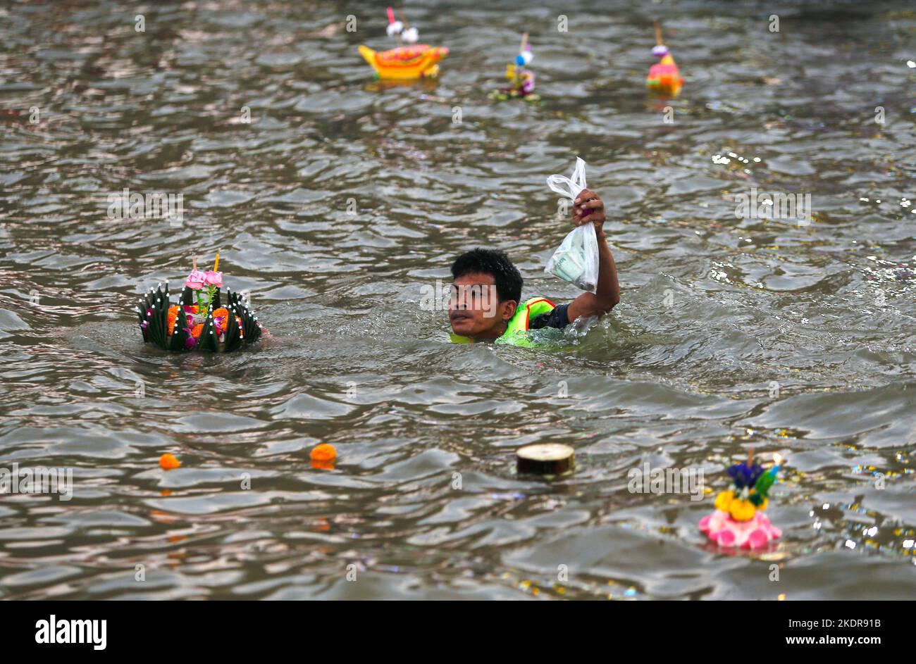 A man carries a Krathong in the Chao Phraya River during the Loy ...