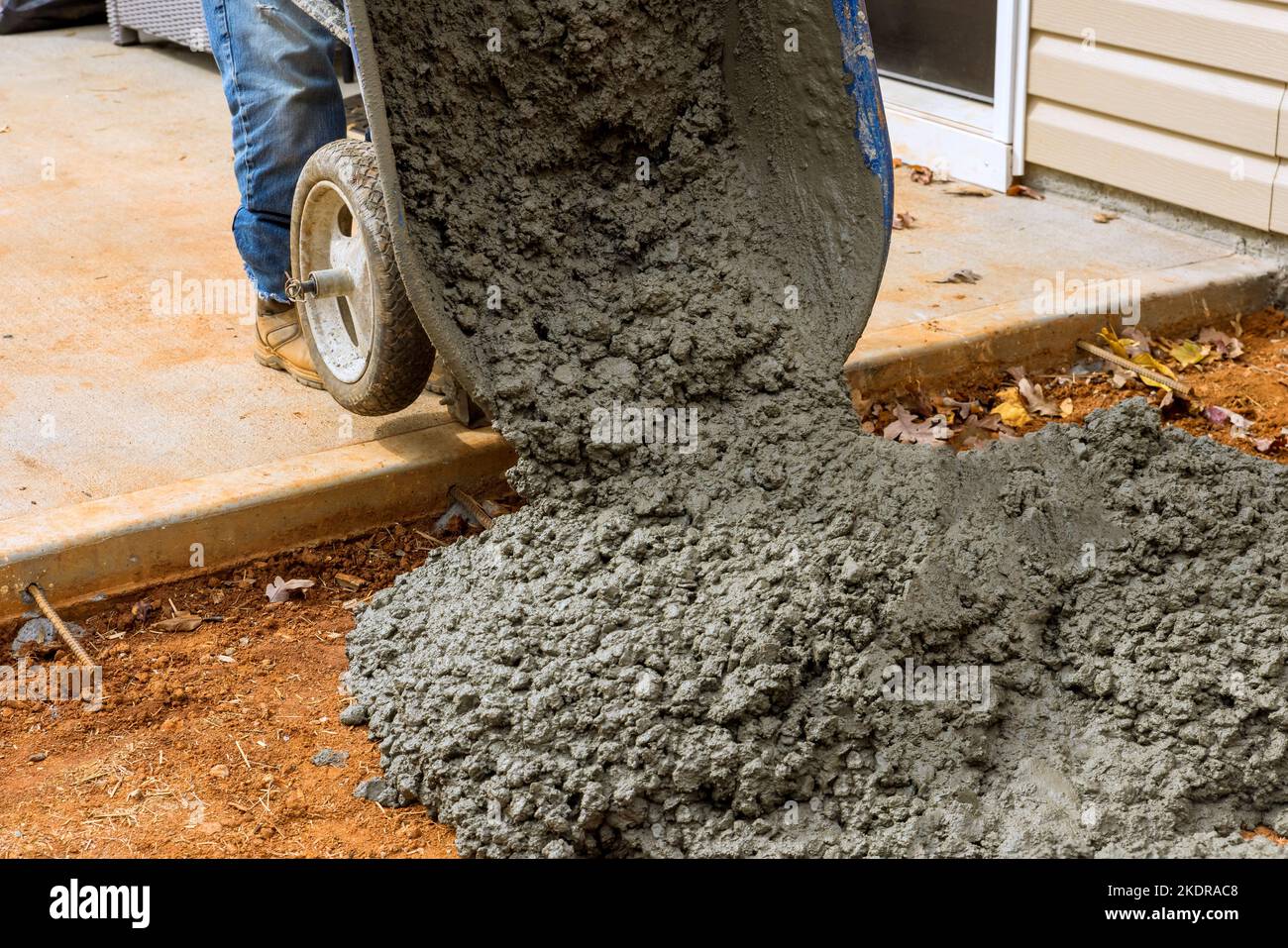 Construction worker pours cement concrete sidewalk created on side of ...