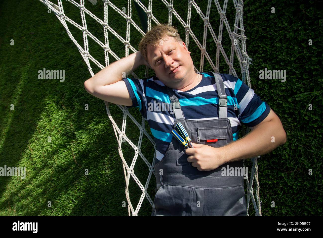 A man after work rests lying in a hammock shade of trees Stock Photo ...
