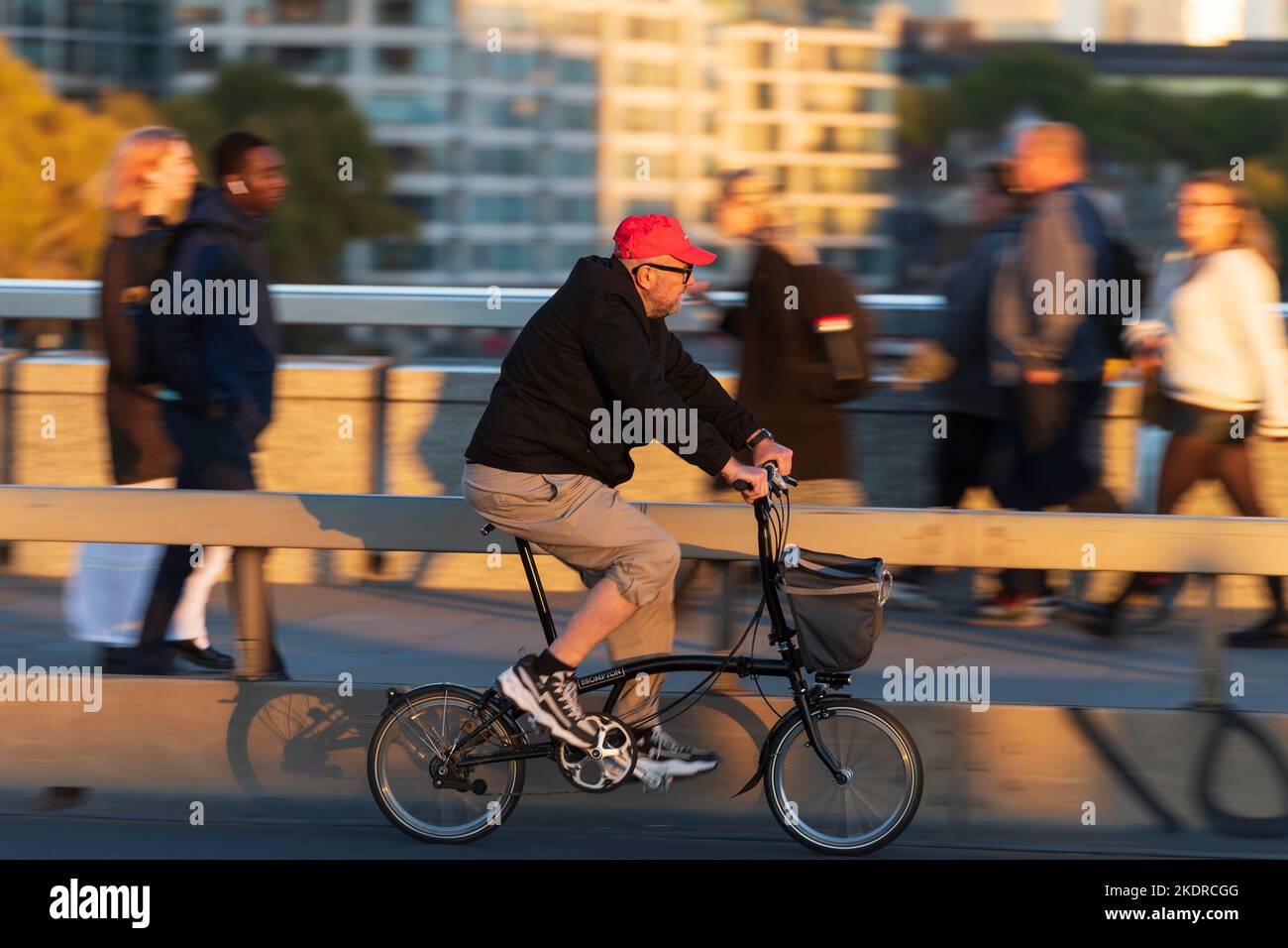A male commuter riding a Brompton folding bicycle across London Bridge ...
