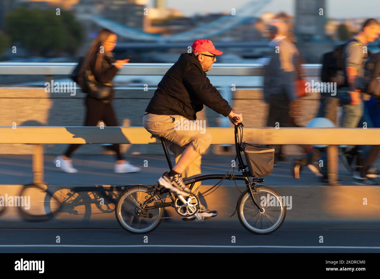 A male commuter riding a Brompton folding bicycle across London Bridge ...