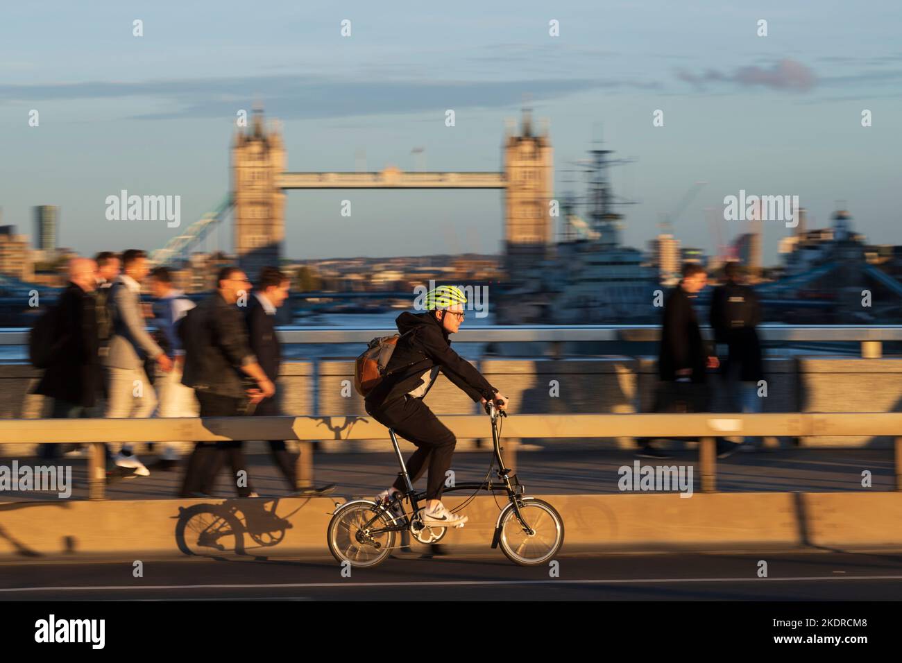 A male commuter riding a Brompton folding bicycle across London Bridge ...