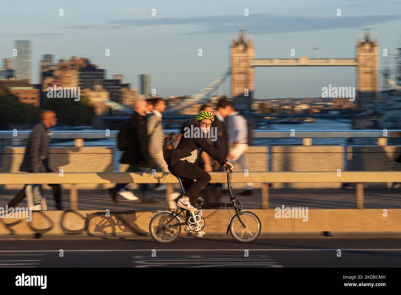 A male commuter riding a Brompton folding bicycle across London Bridge ...