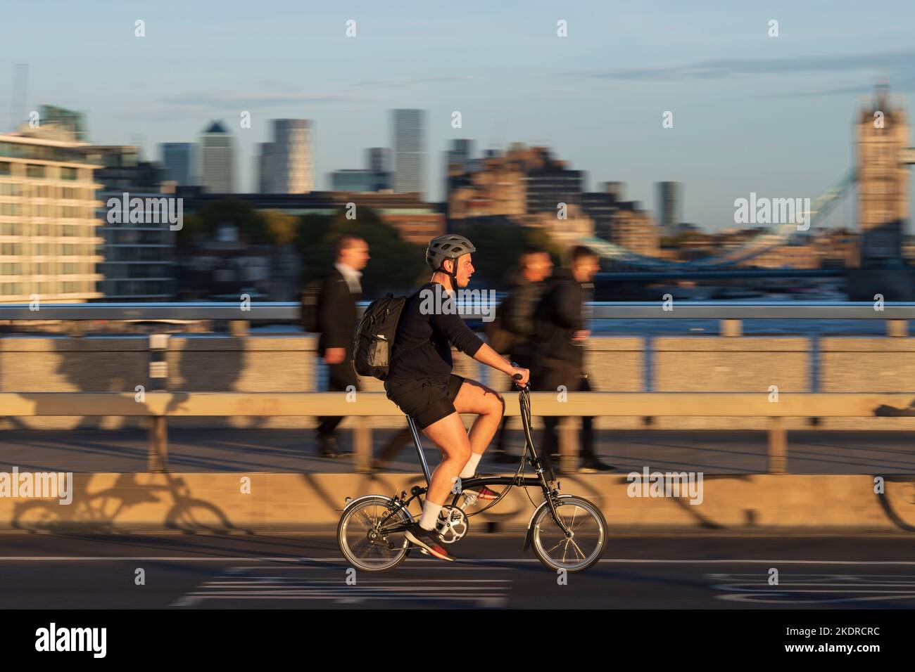 A male commuter riding a Brompton folding bicycle across London Bridge ...