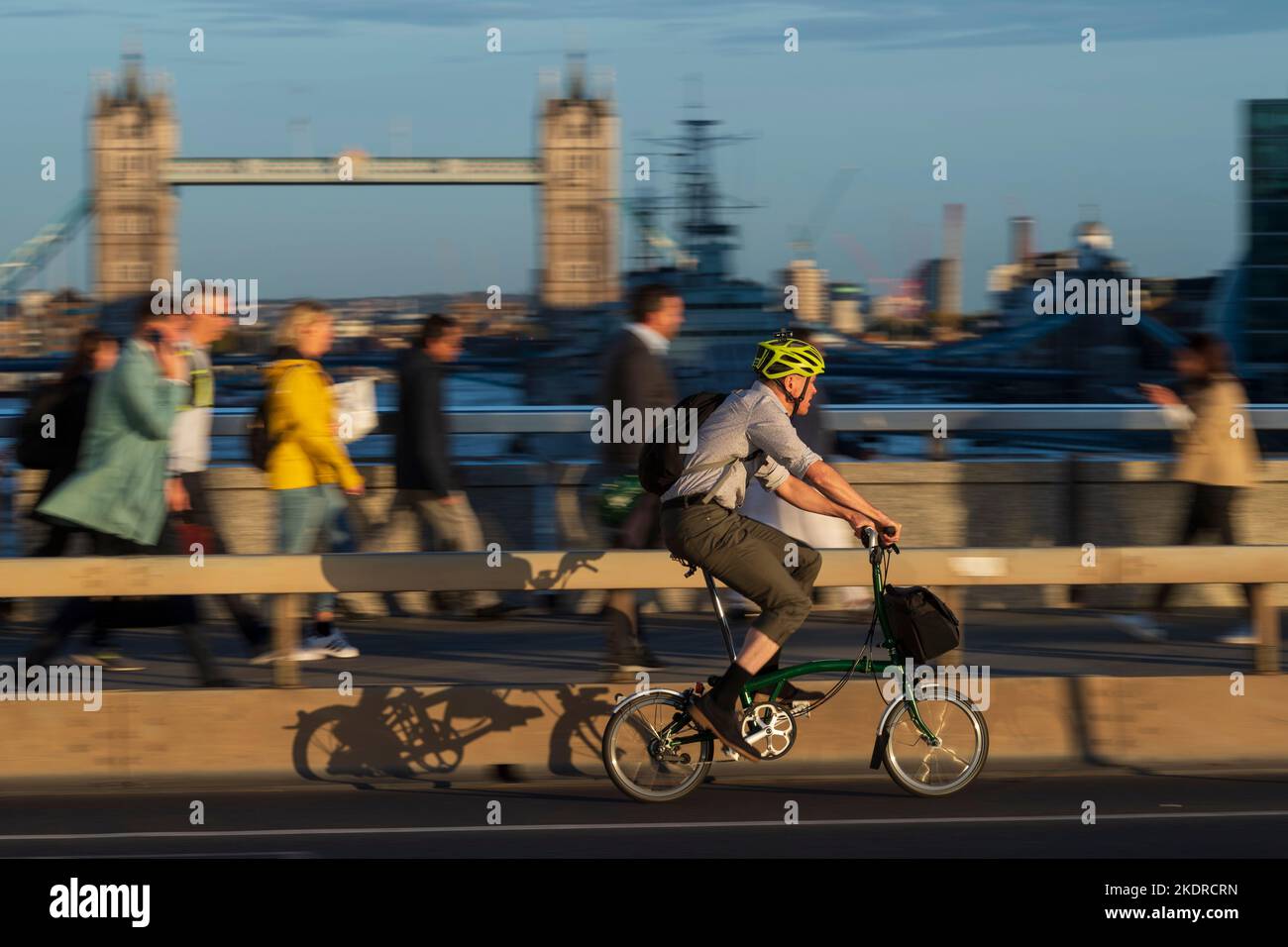 A male commuter riding a Brompton folding bicycle across London Bridge ...
