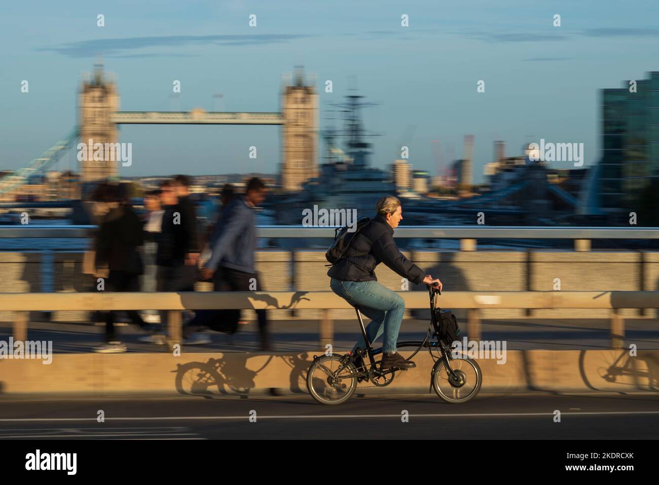 A female commuter riding a Brompton folding bicycle across London ...