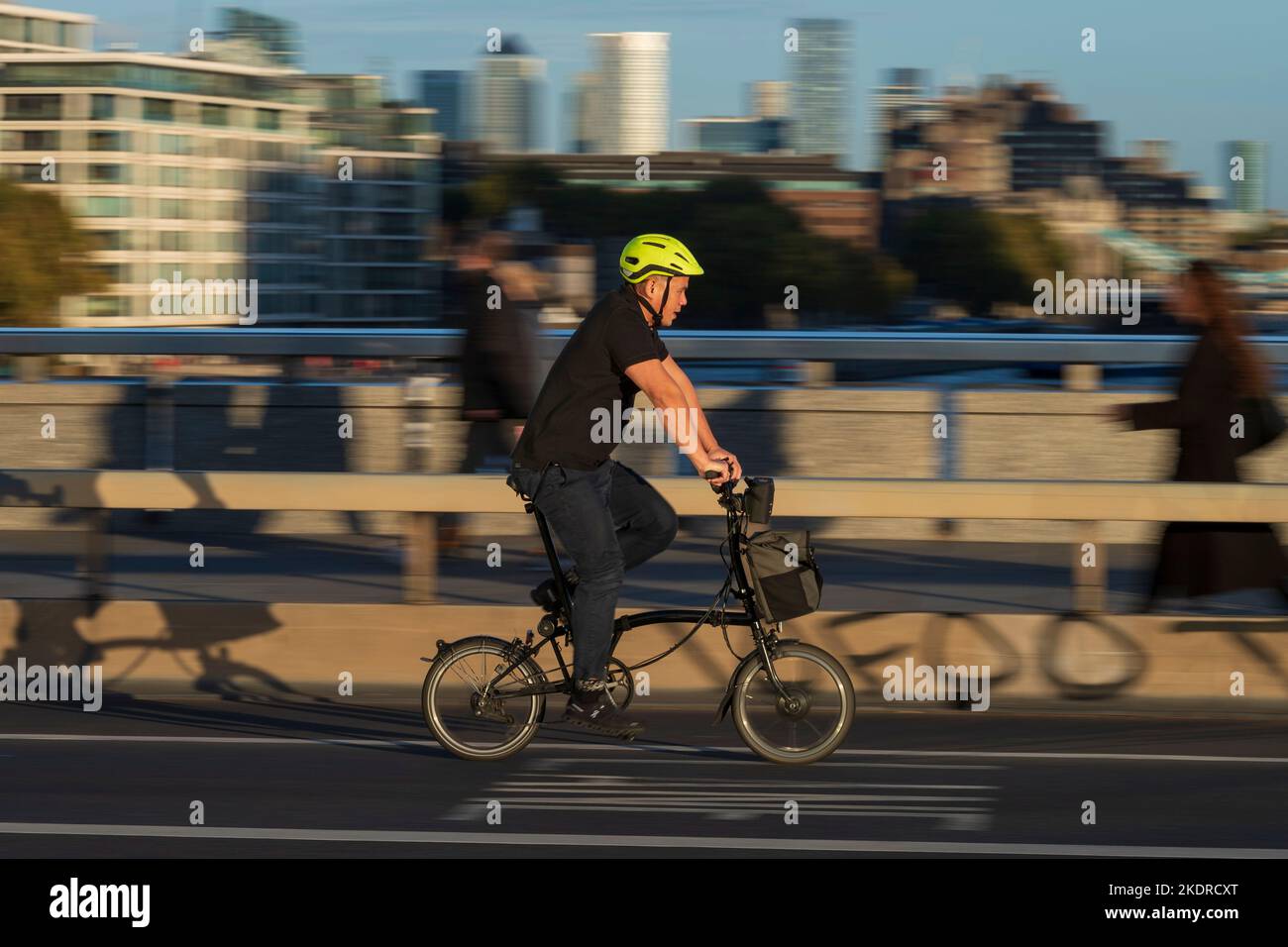 A male commuter riding a Brompton folding bicycle across London Bridge ...