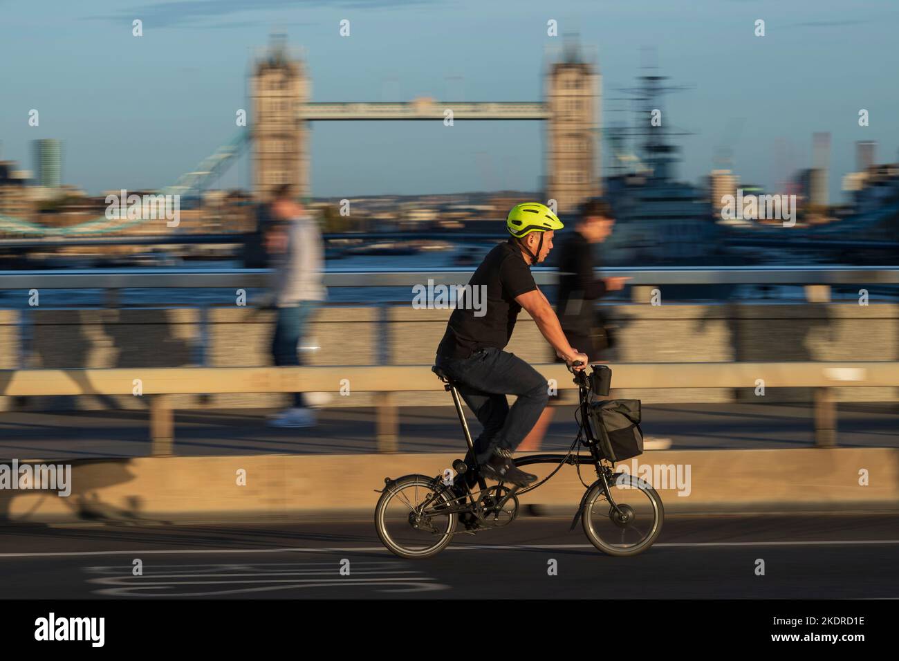 A male commuter riding a Brompton folding bicycle across London Bridge ...
