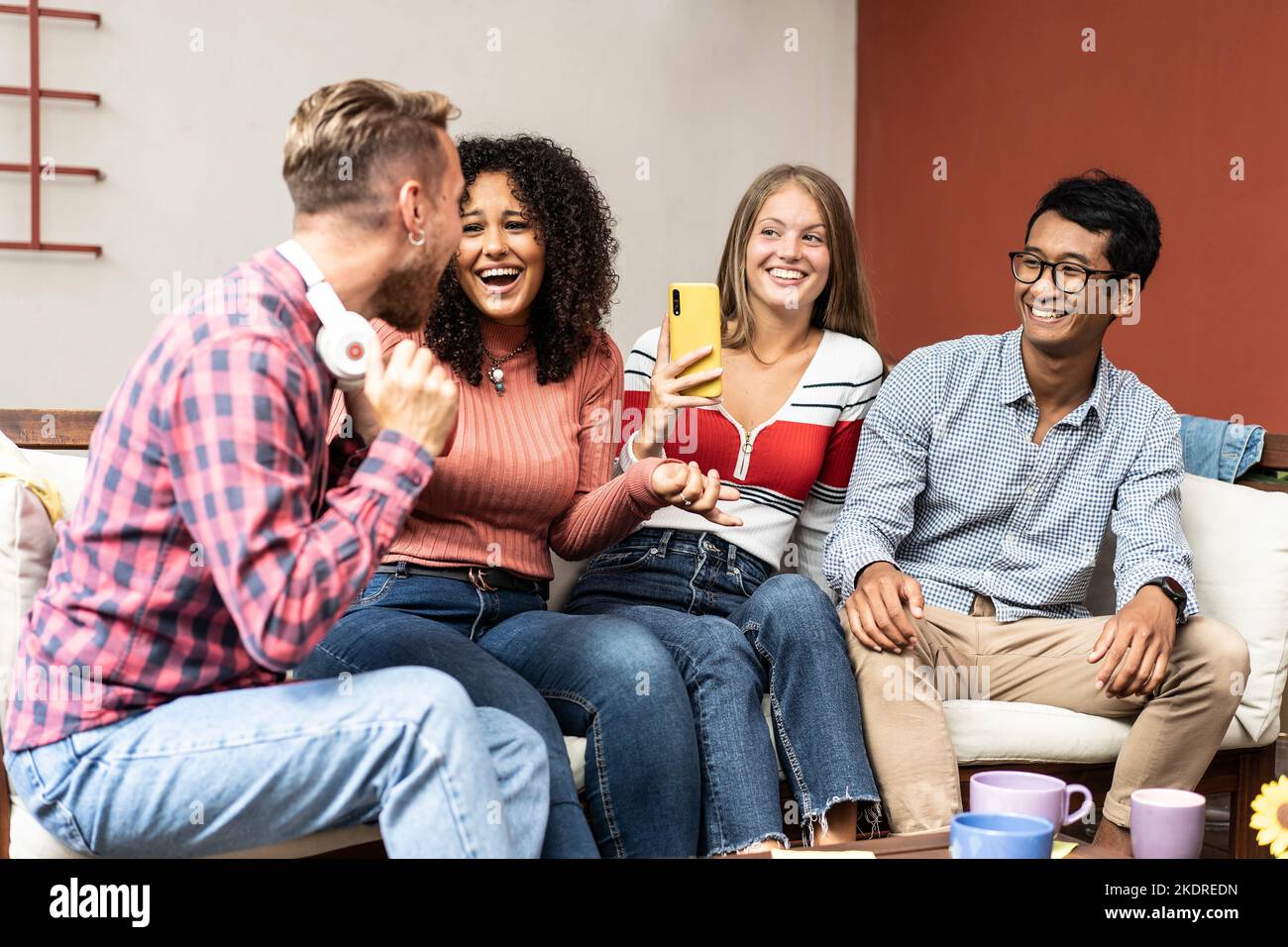 Young university students having fun at the campus hall listening to ...