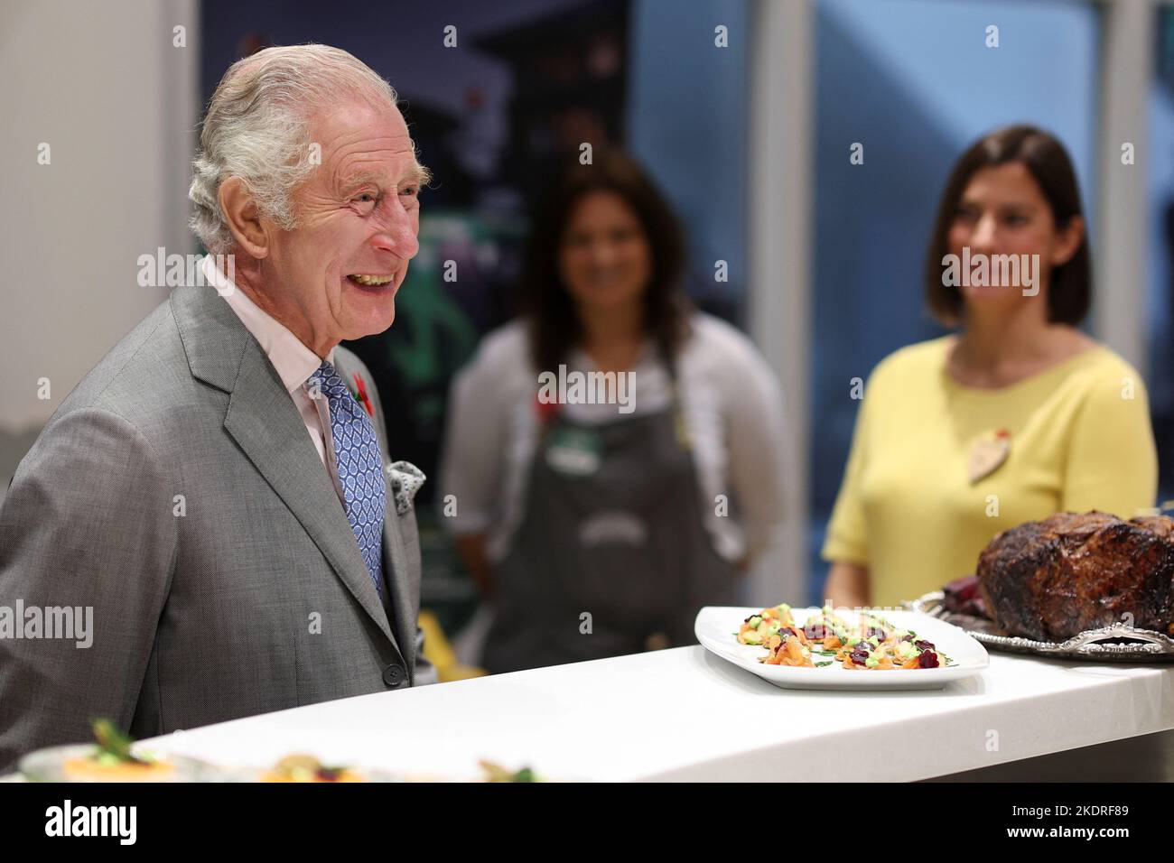 King Charles III smiles as he speaks to members of staff during a visit ...