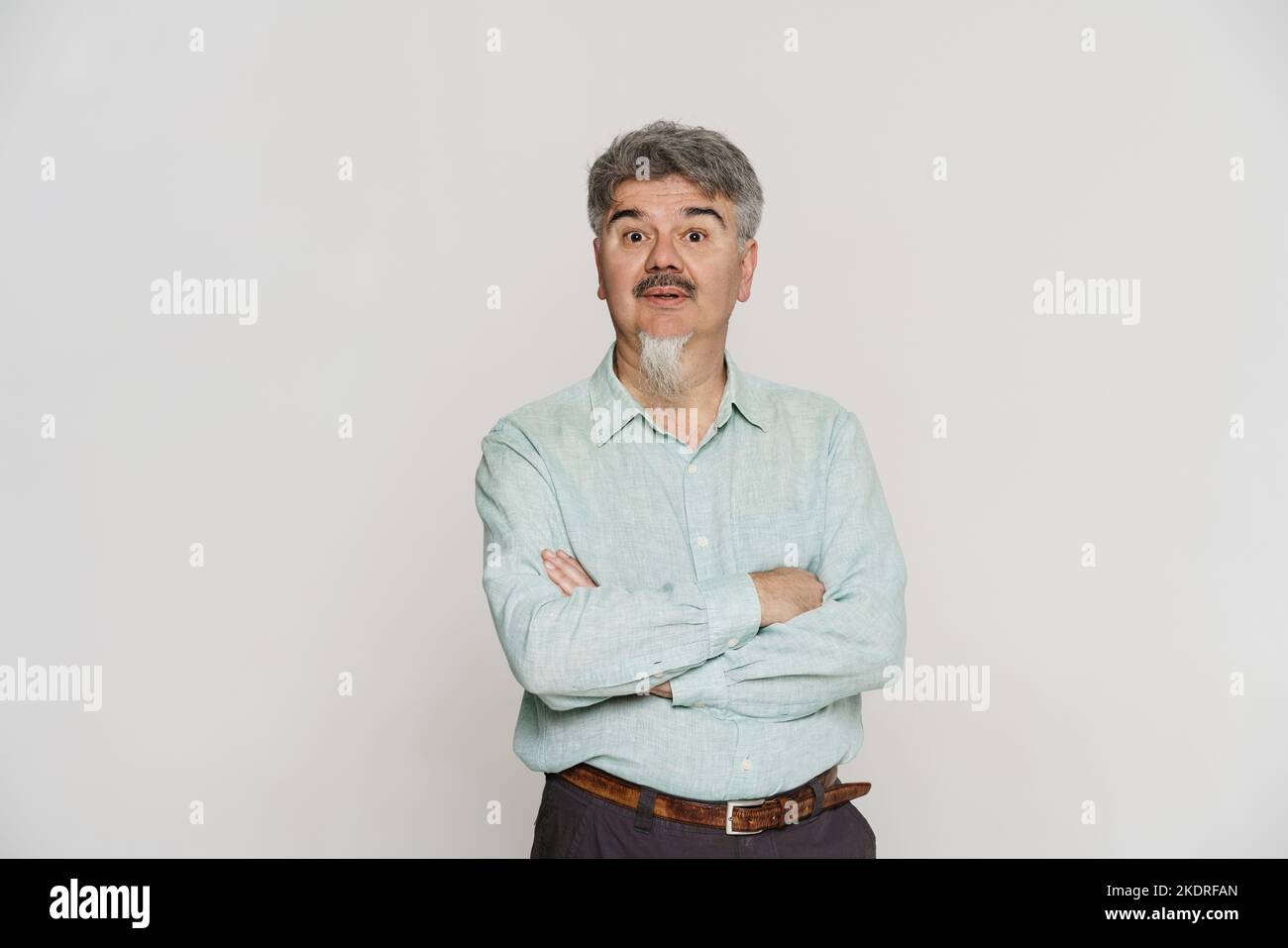 Mature Man With Grey Beard Expressing Surprise At Camera Isolated Over