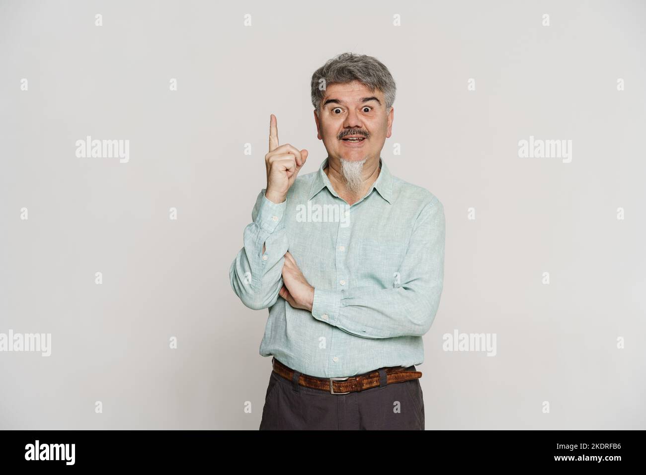 Mature man pointing finger upward while expressing surprise isolated ...