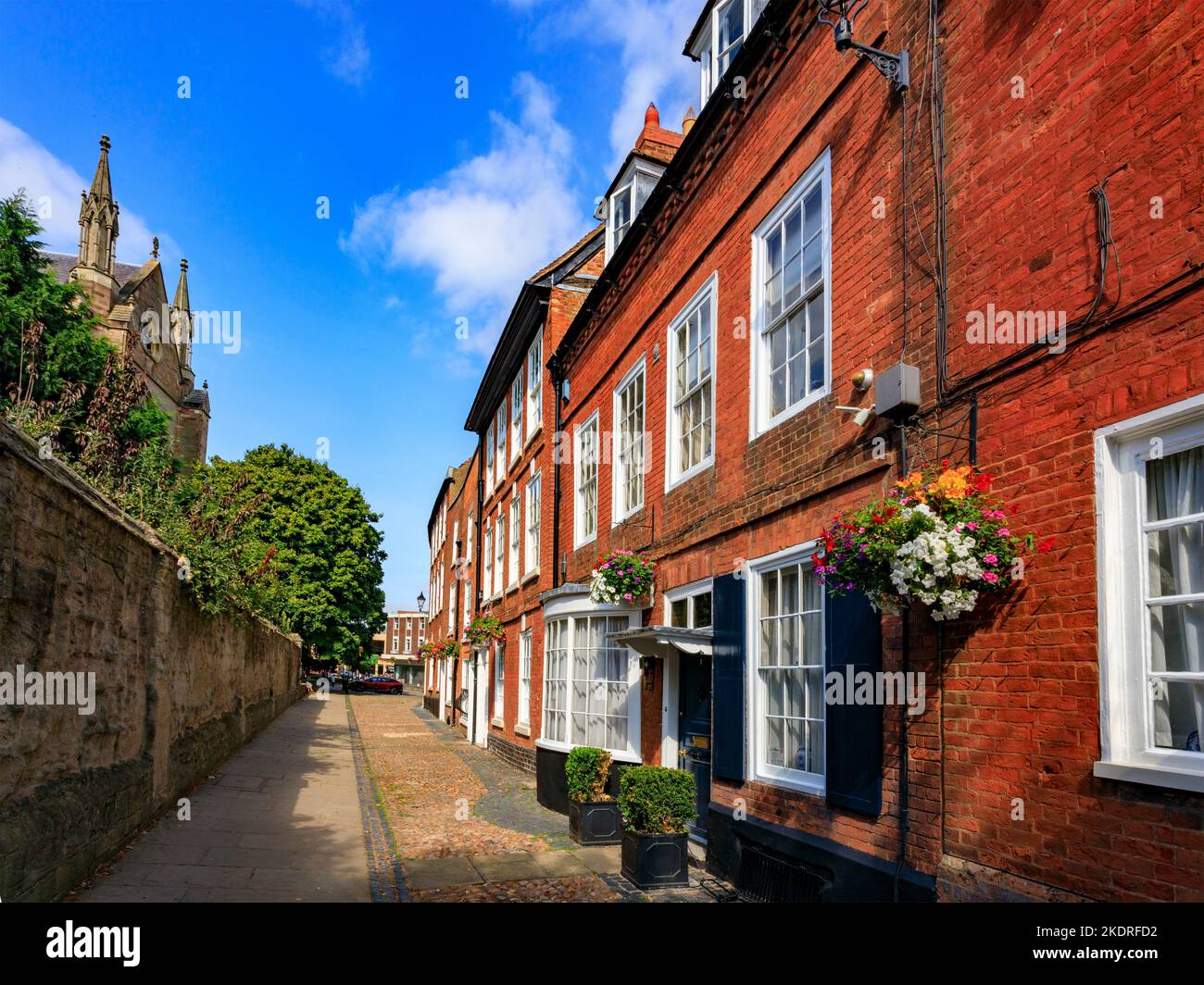 An elegant red brick terrace with colourful hanging baskets in the ...