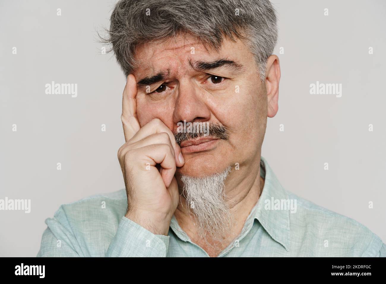 Senior sad man with mustache and beard looking at camera isolated over ...