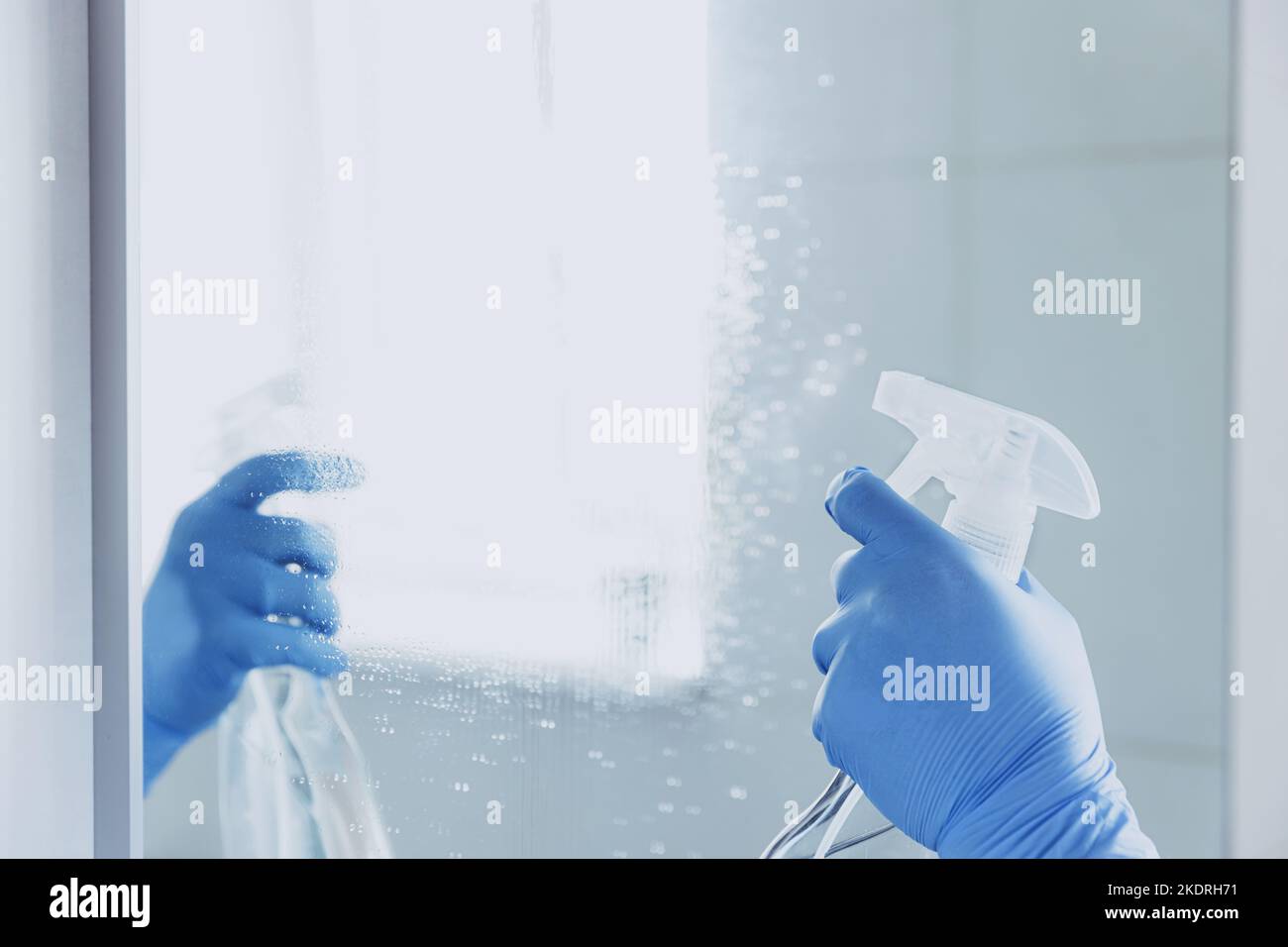 Cropped view of housekeeper woman hand in rubber blue gloves spraying ...