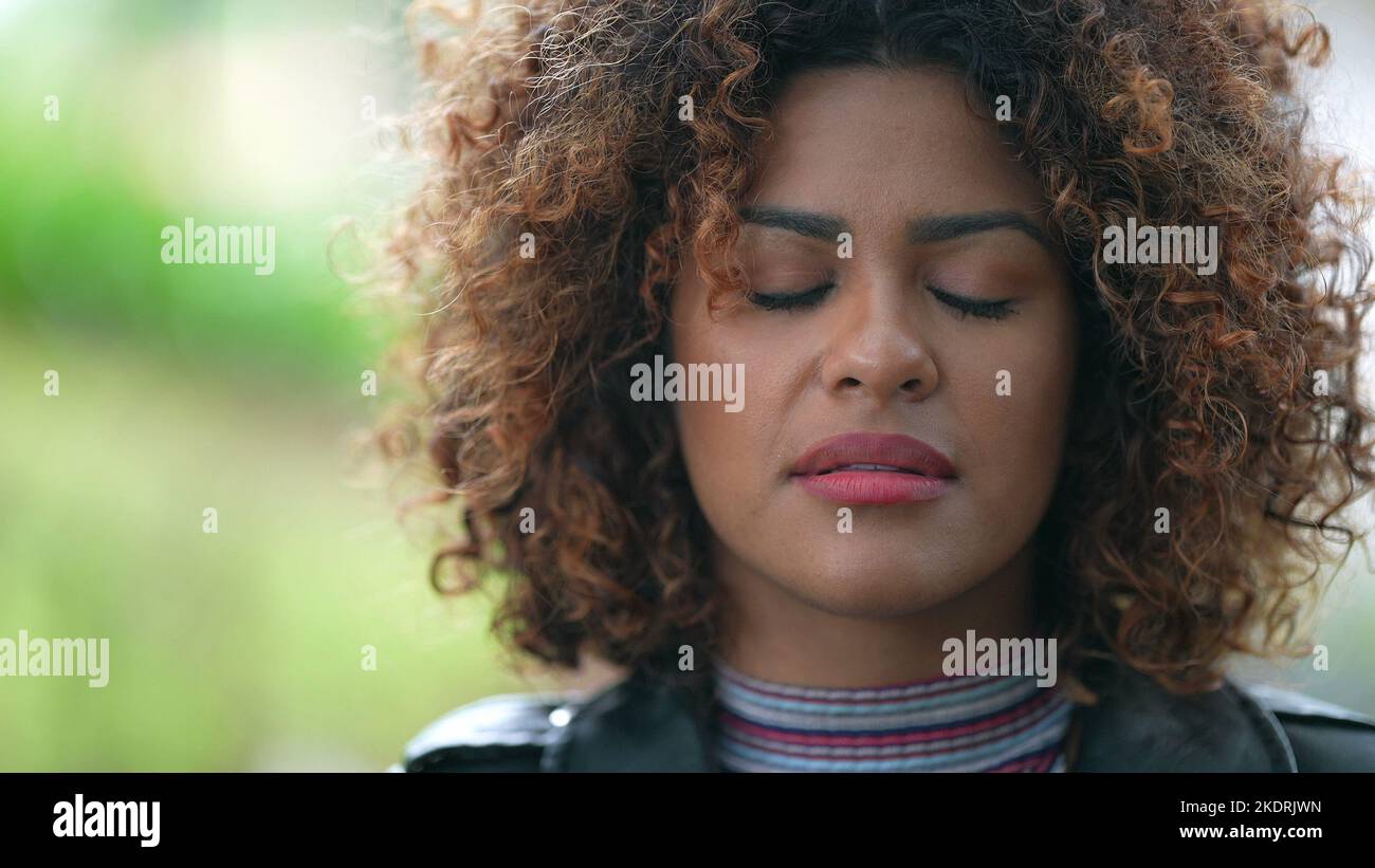 Black African woman taking a deep breath breathing outside closing eyes ...