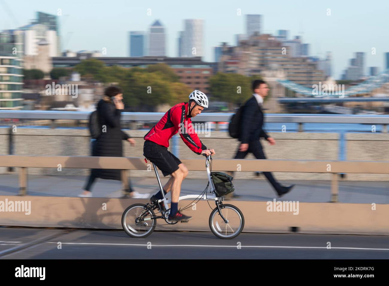 A male commuter riding a Brompton folding bicycle across London Bridge ...