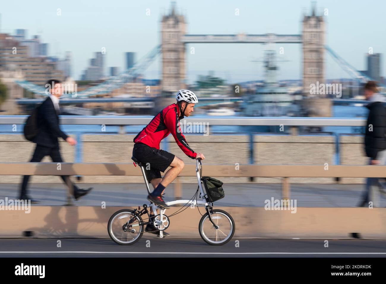 A male commuter riding a Brompton folding bicycle across London Bridge ...