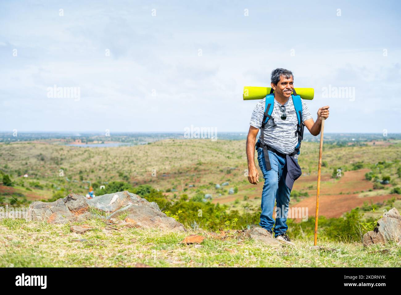 Medium shot of middle aged man with travel backpack climbing mountian ...