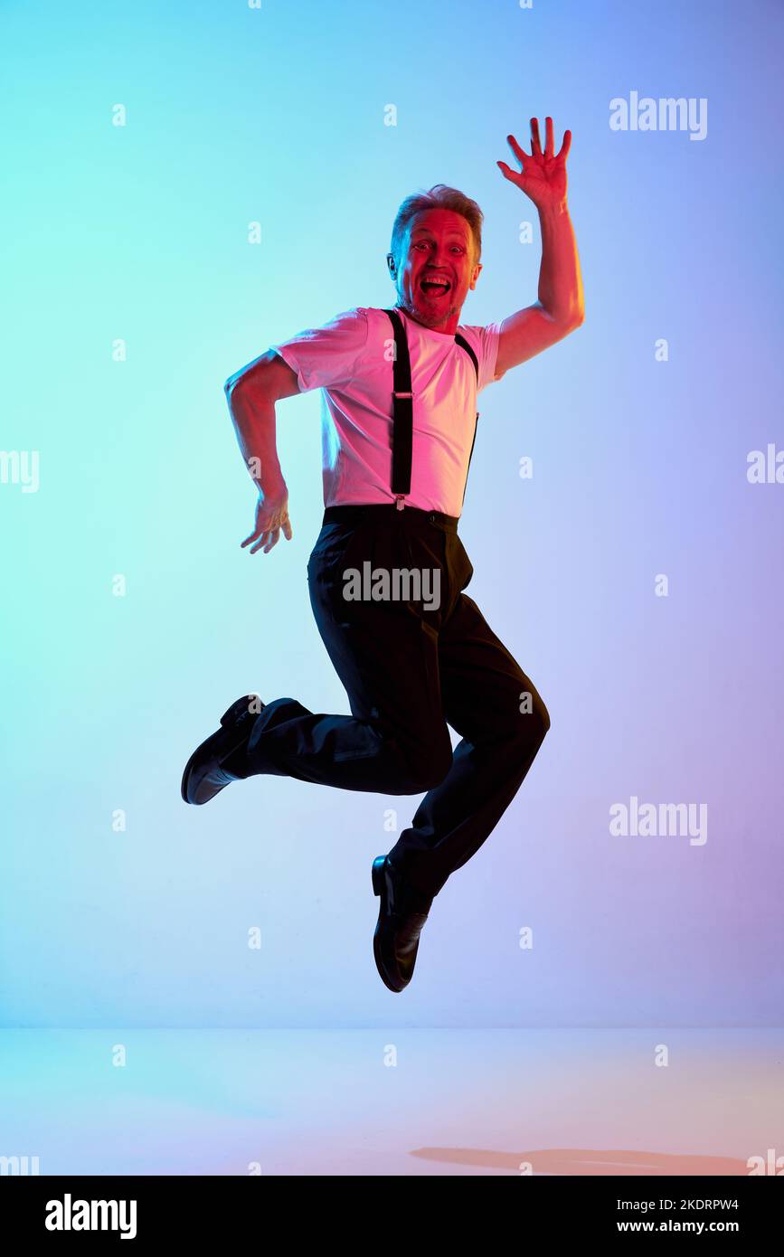 Portrait of mature man in shirt posing, cheerfully jumping isolated ...