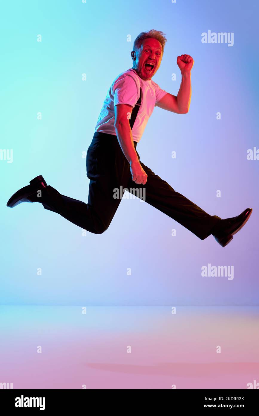 Portrait of mature man in shirt posing, cheerfully jumping isolated ...