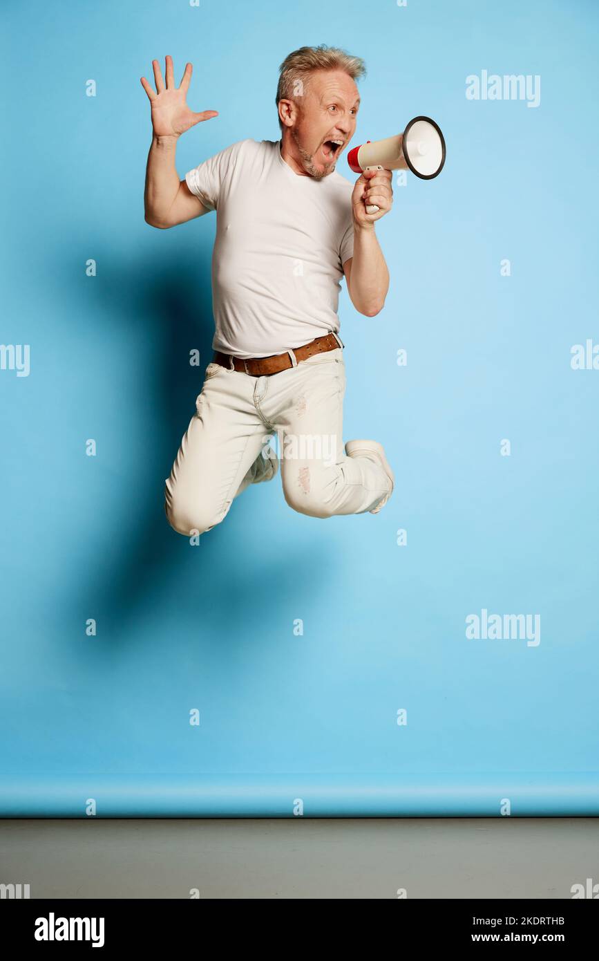 Portrait of mature man in white casual clothes posing, jumping and ...