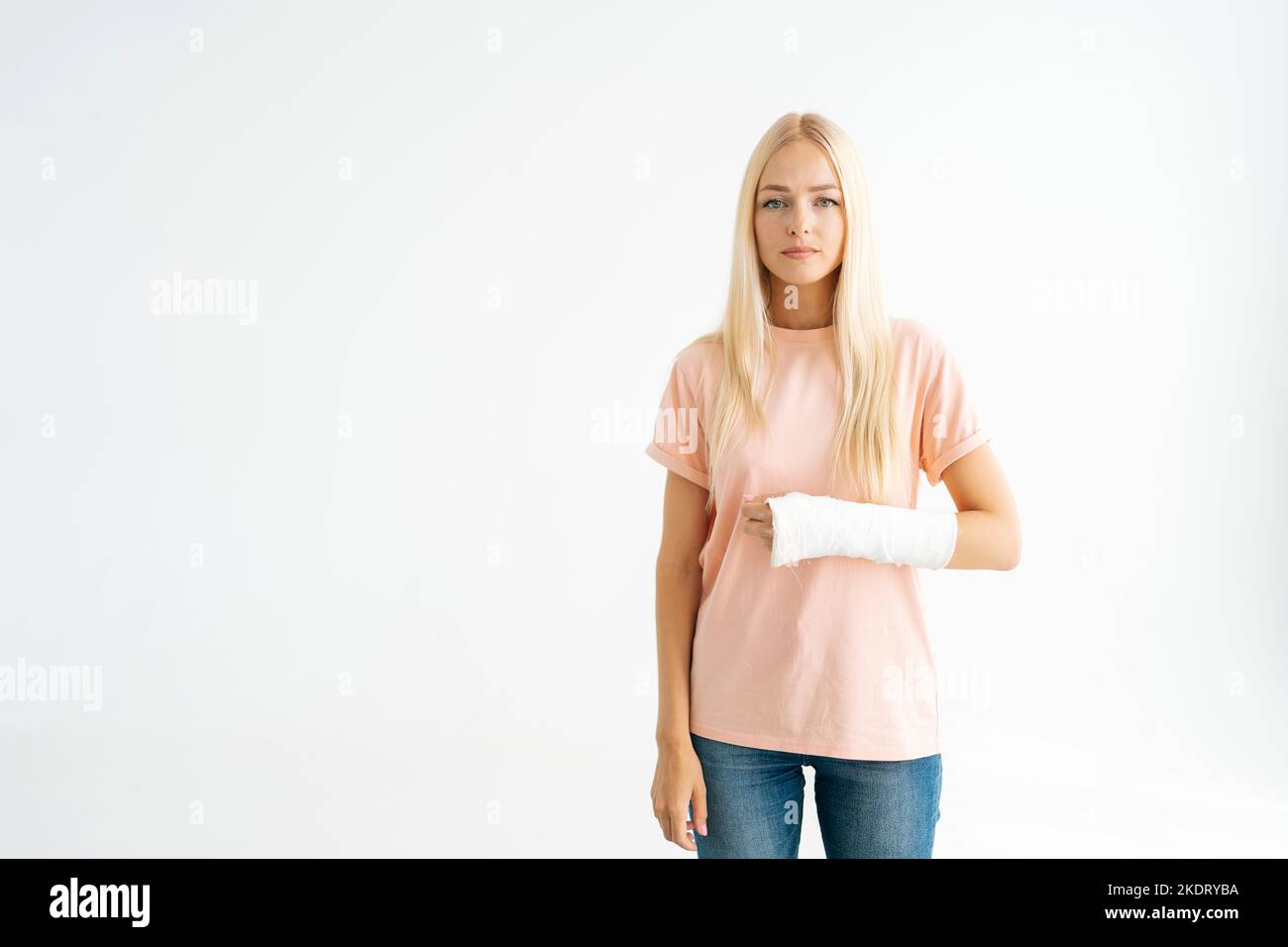 Studio portrait of sad injured blonde young woman with broken arm ...