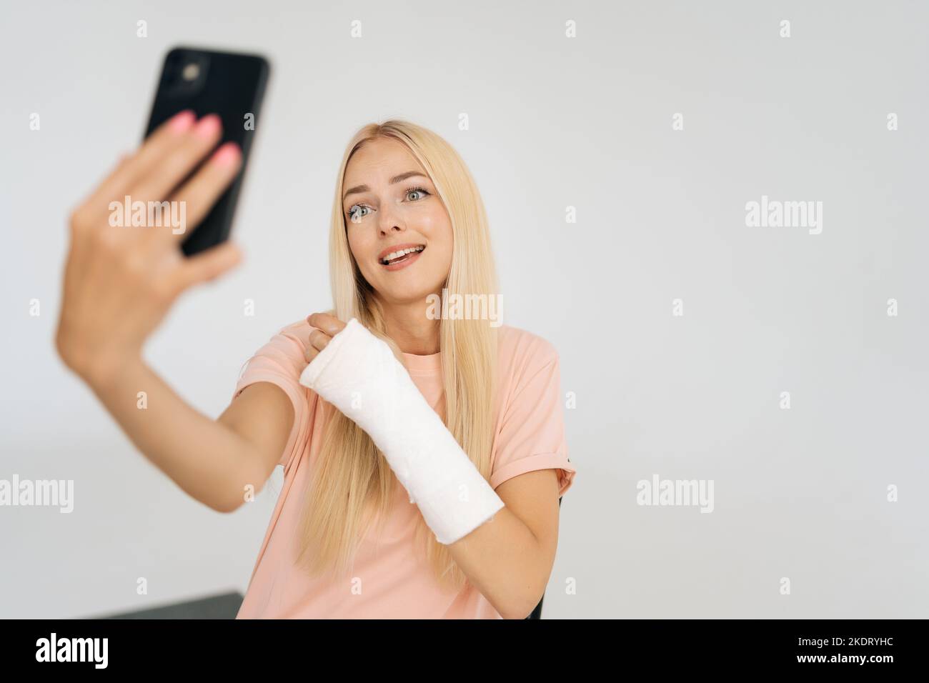 Pretty young blonde woman with broken arm wrapped in plaster bandage ...