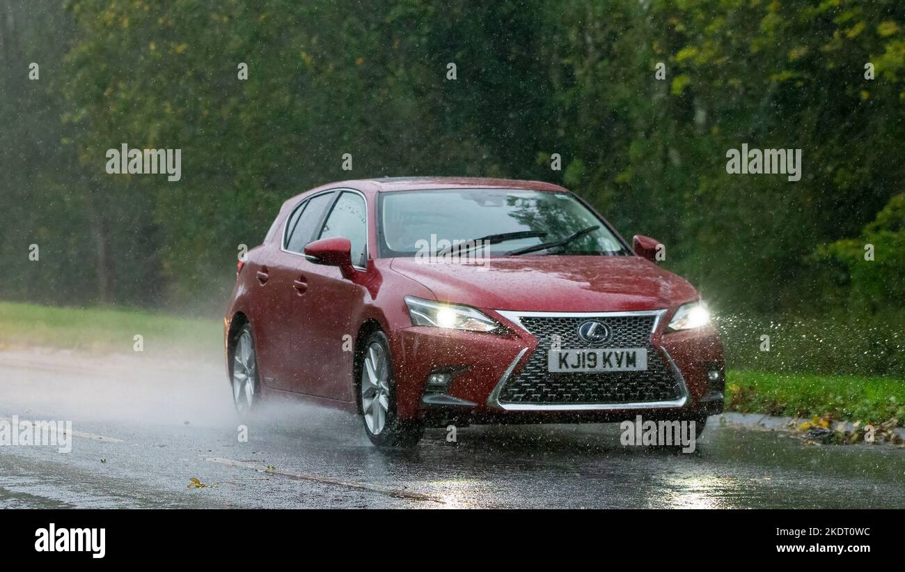 2019 red hybrid electric Lexus CT car driving in the rain on a wet road ...