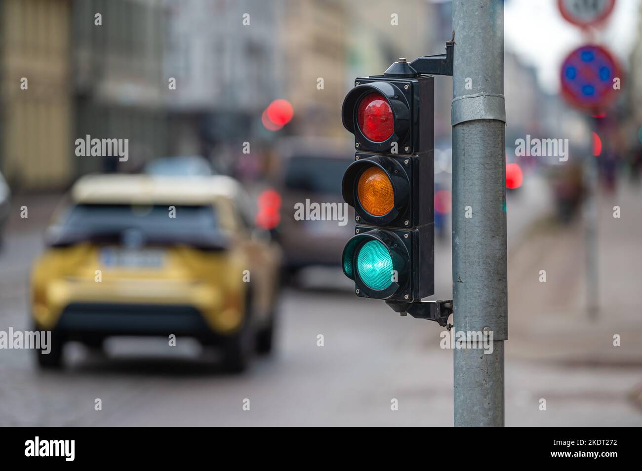 a city crossing with a semaphore on blurred background with cars in the ...
