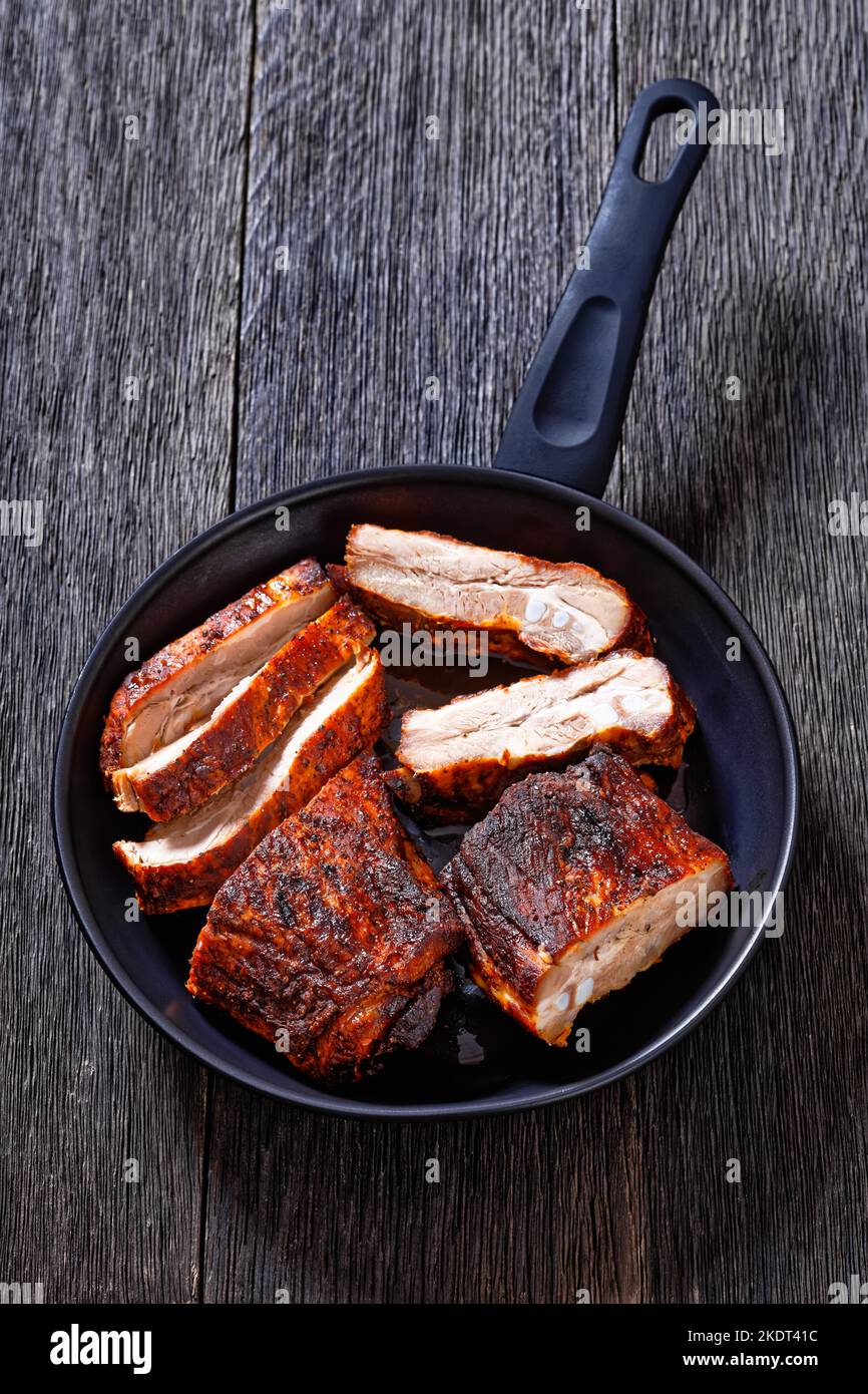 roast baby back pork meaty ribs in a pan on dark wooden table, vertical ...