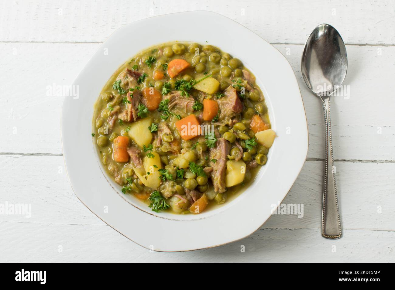 Plate with pea stew on white wooden background from above Stock Photo ...