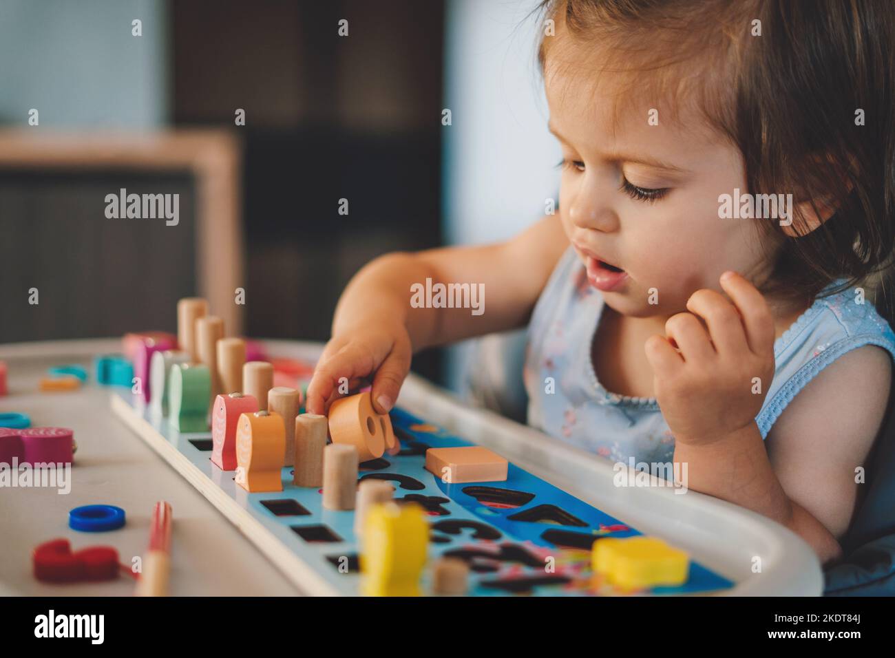Baby girl playing with different color wooden elements making tasks for ...