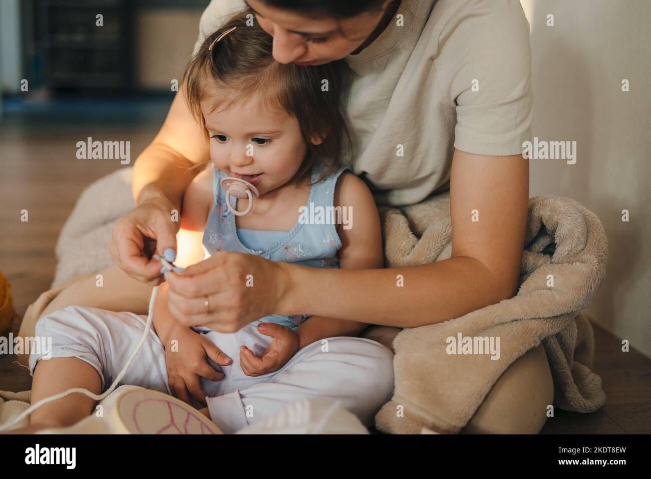 Baby girl watching carefully how her mother sews. Homeschooling ...