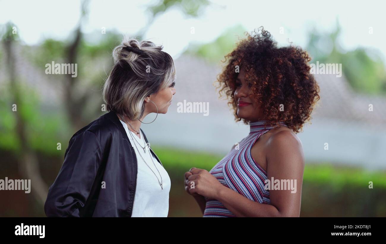 Two diverse friends talking outside at park. people conversation Stock ...