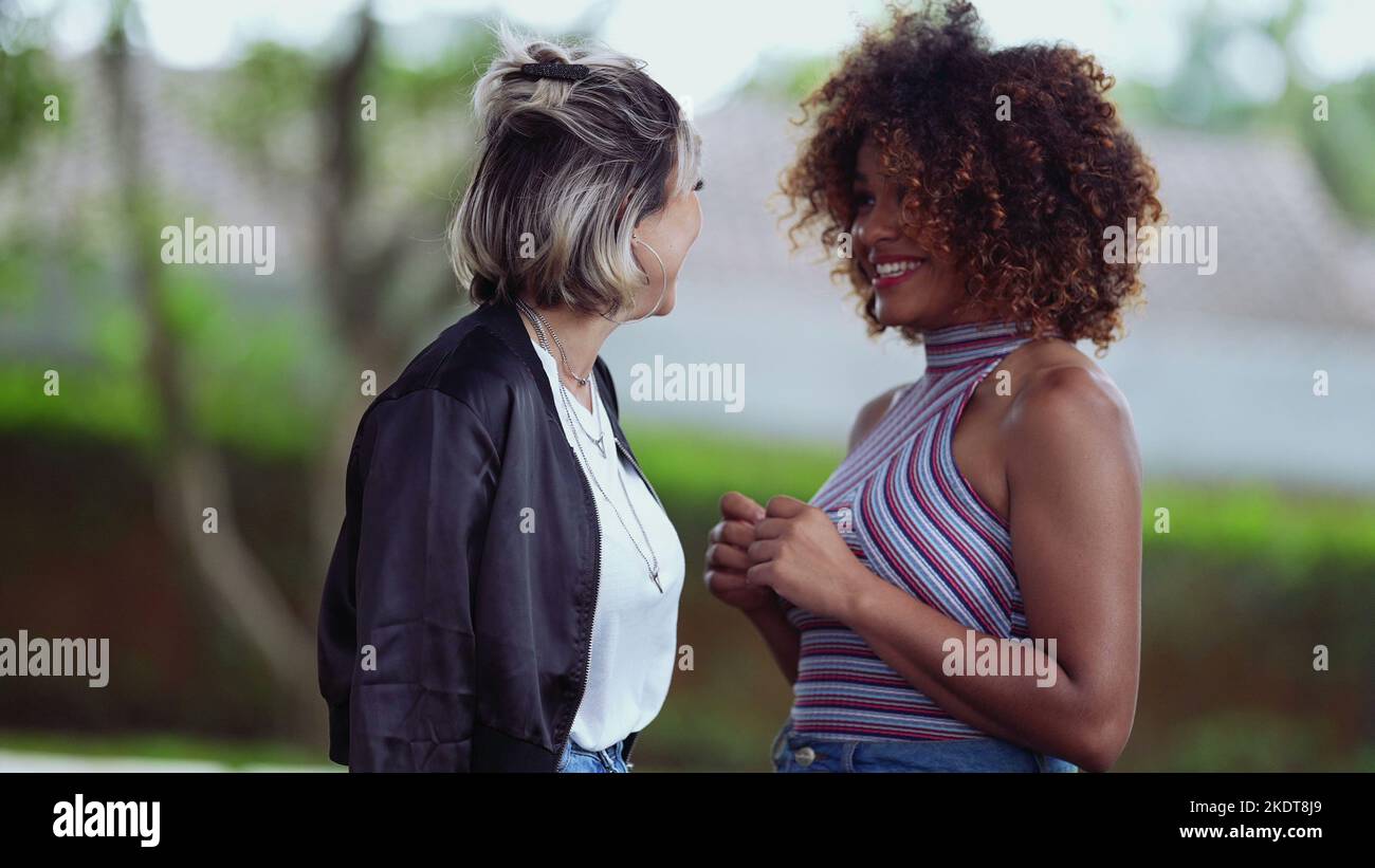 Two diverse friends talking outside at park. people conversation Stock ...