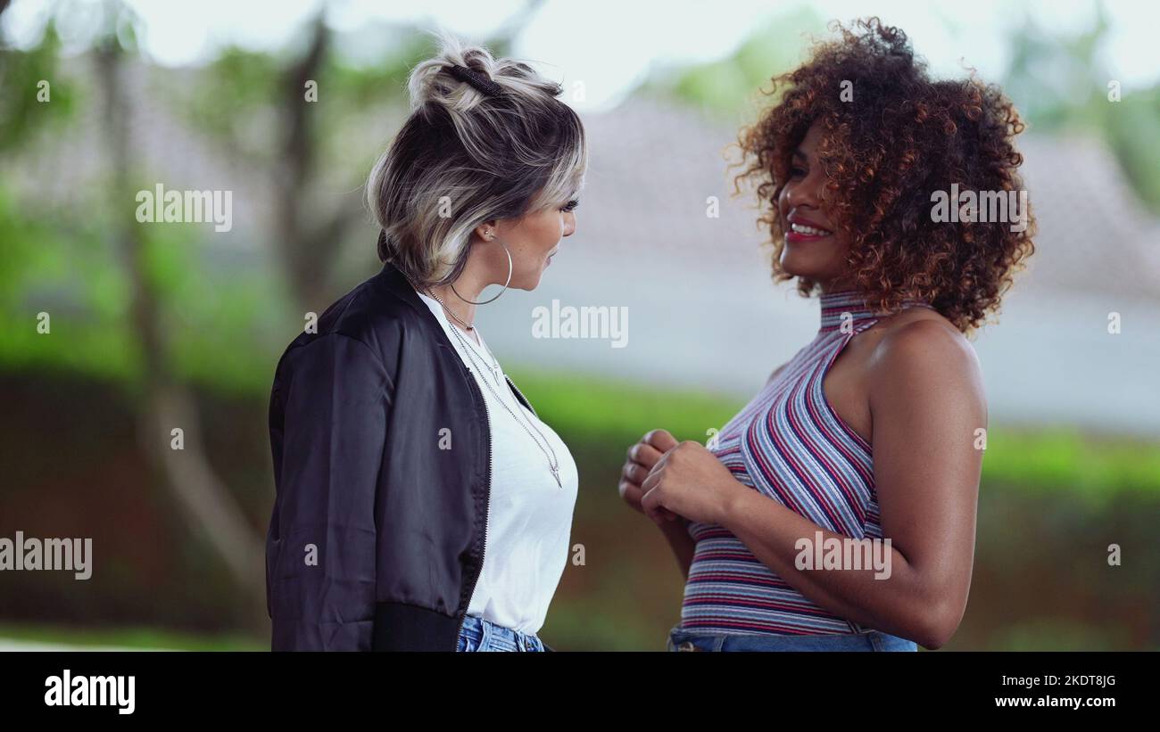 Two diverse friends talking outside at park. people conversation Stock ...