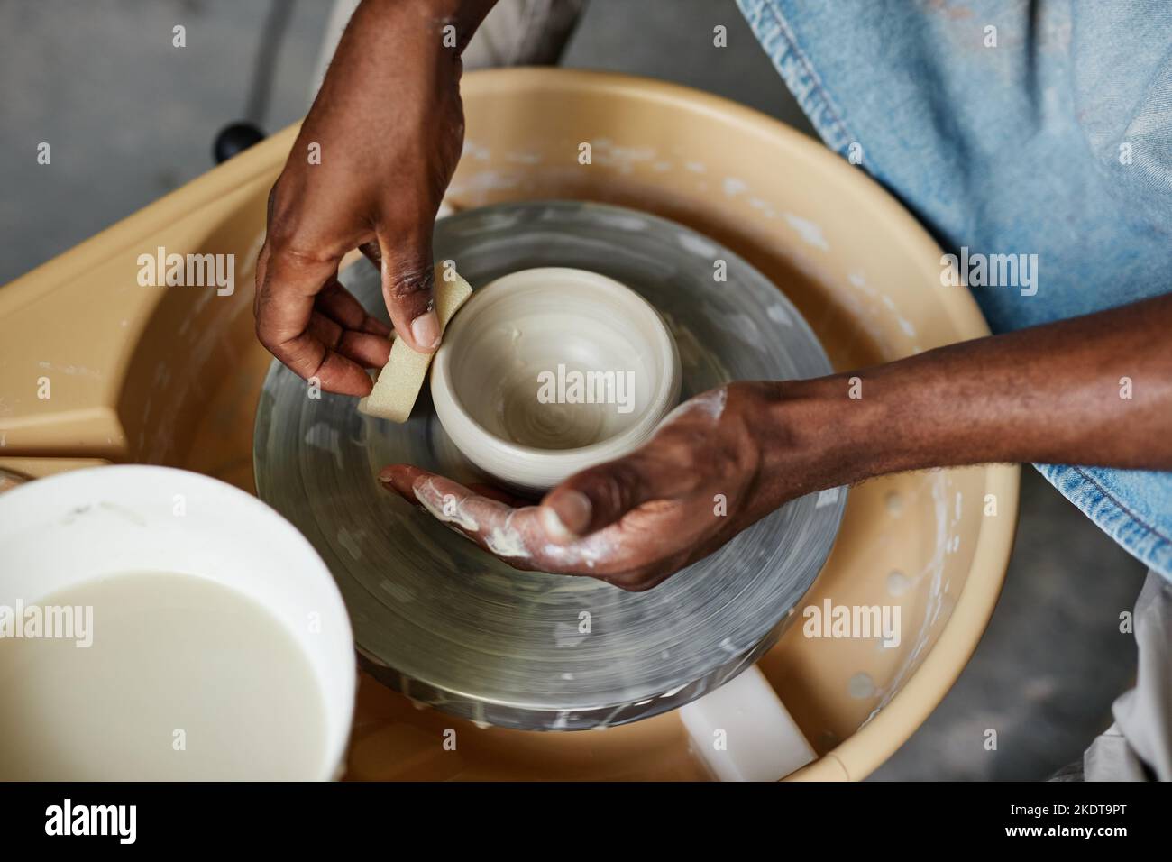 Top view of male hands of black young man using pottery wheel and ...