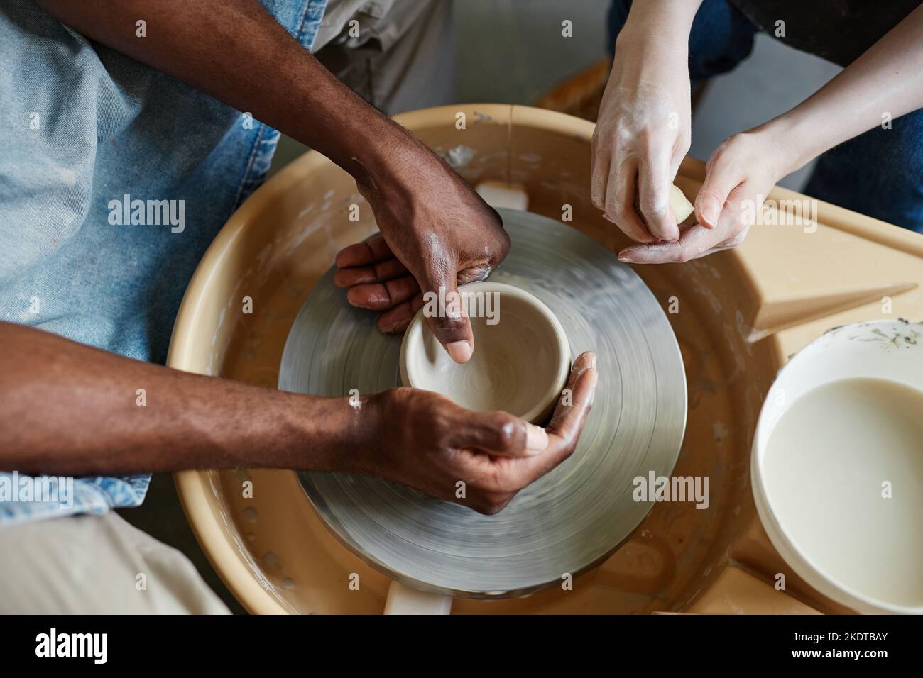 Top view of young couple using pottery wheel together and creating ...