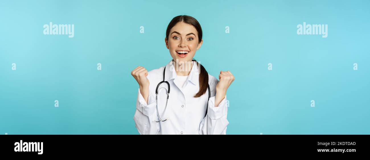 Happy and excited young female doctor, physician celebrating, achieve ...