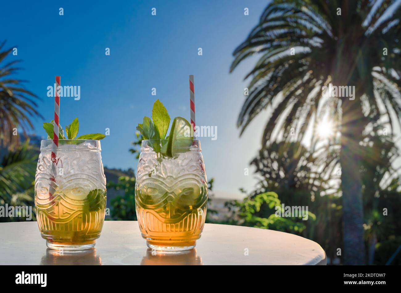 two drinks with a tropical landscape in the background Stock Photo - Alamy