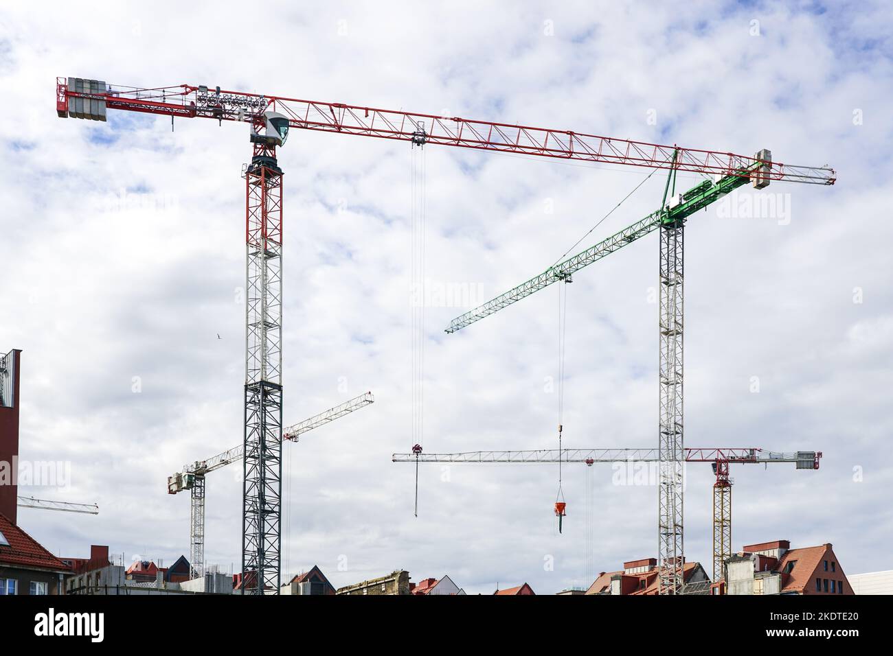 Several tall construction tower cranes in city construction sites ...