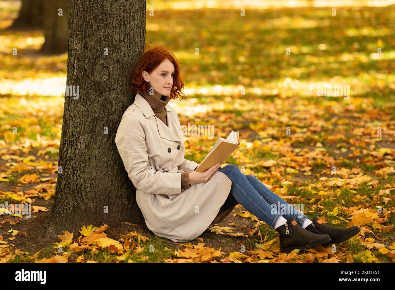 Serious smart caucasian millennial woman with red hair in raincoat ...