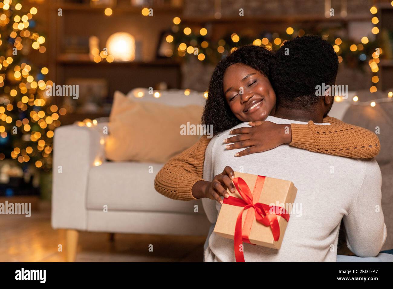 Smiling millennial african american woman hug man with present box in ...