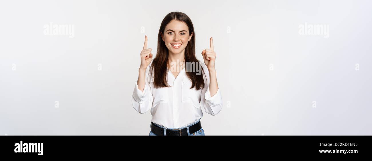 Smiling confident pretty woman, pointing fingers up, showing logo ...
