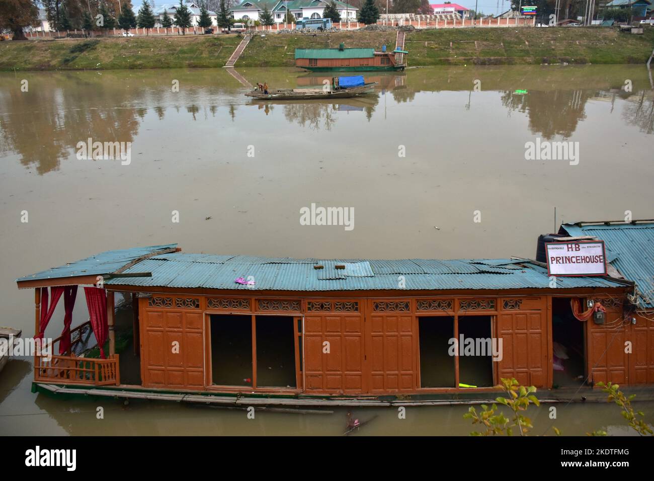 Boatmen row their boat next to capsized residential houseboat in the ...