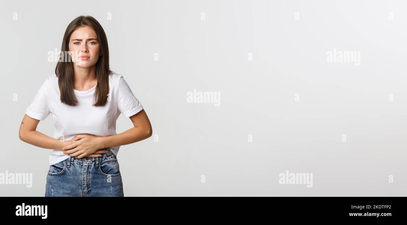Woman having stomach ache, bending and holding hands on belly, discomfort from menstrual cramps ...