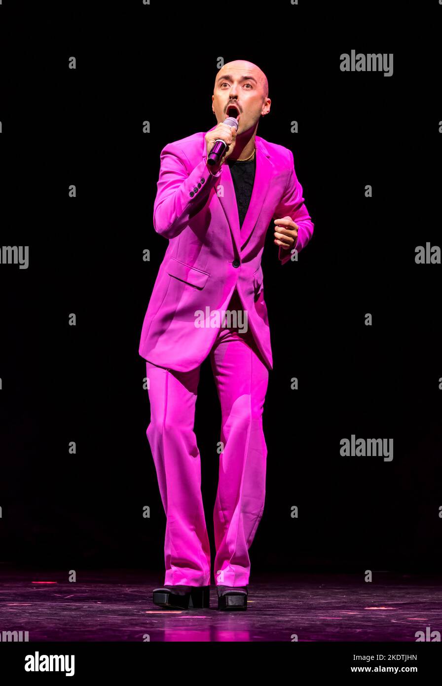 Comedian Rob Madge wearing a pink suit performing on stage during ...
