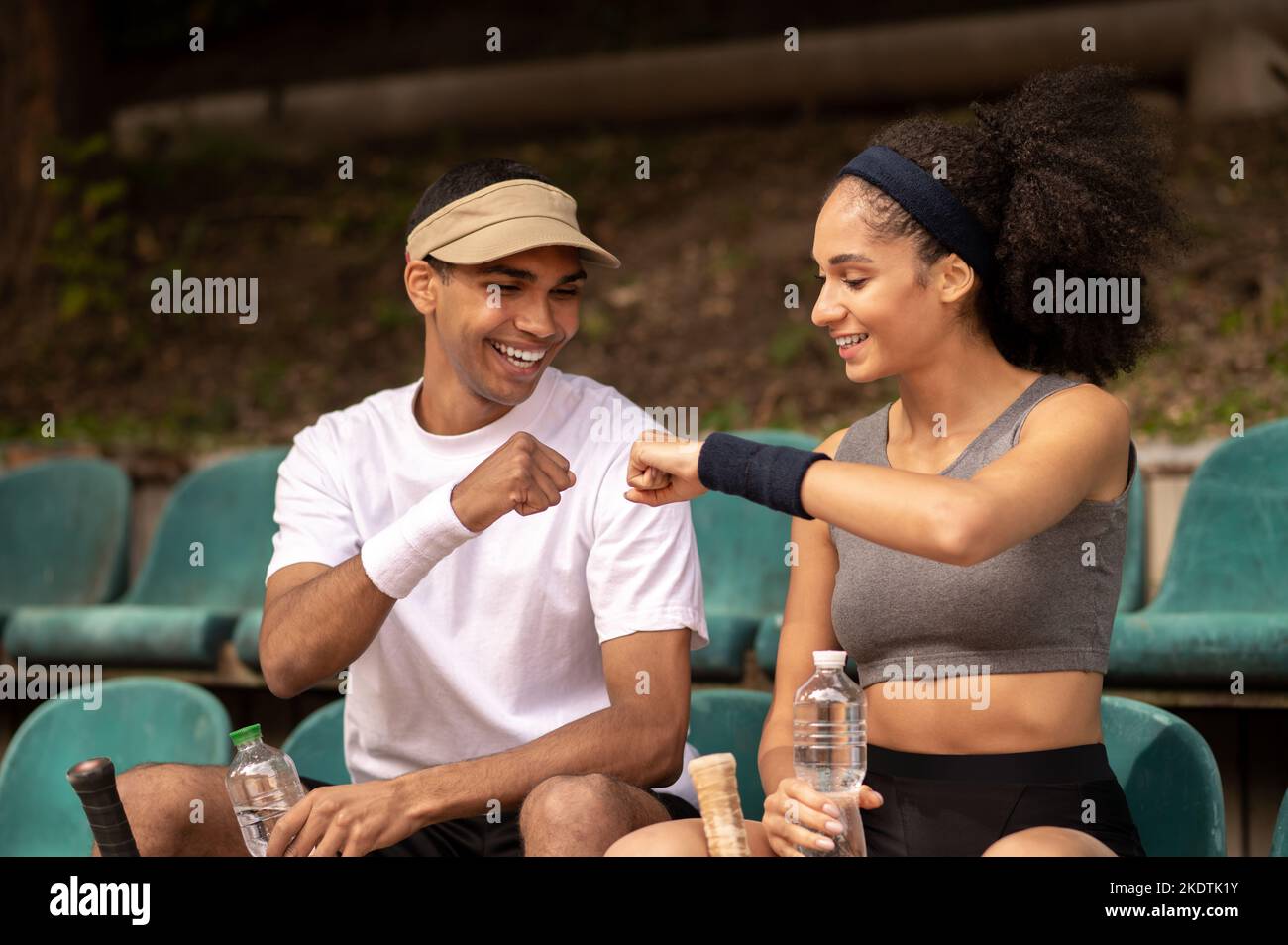 Young man and woman sitting at the tennis court and discussing the game ...